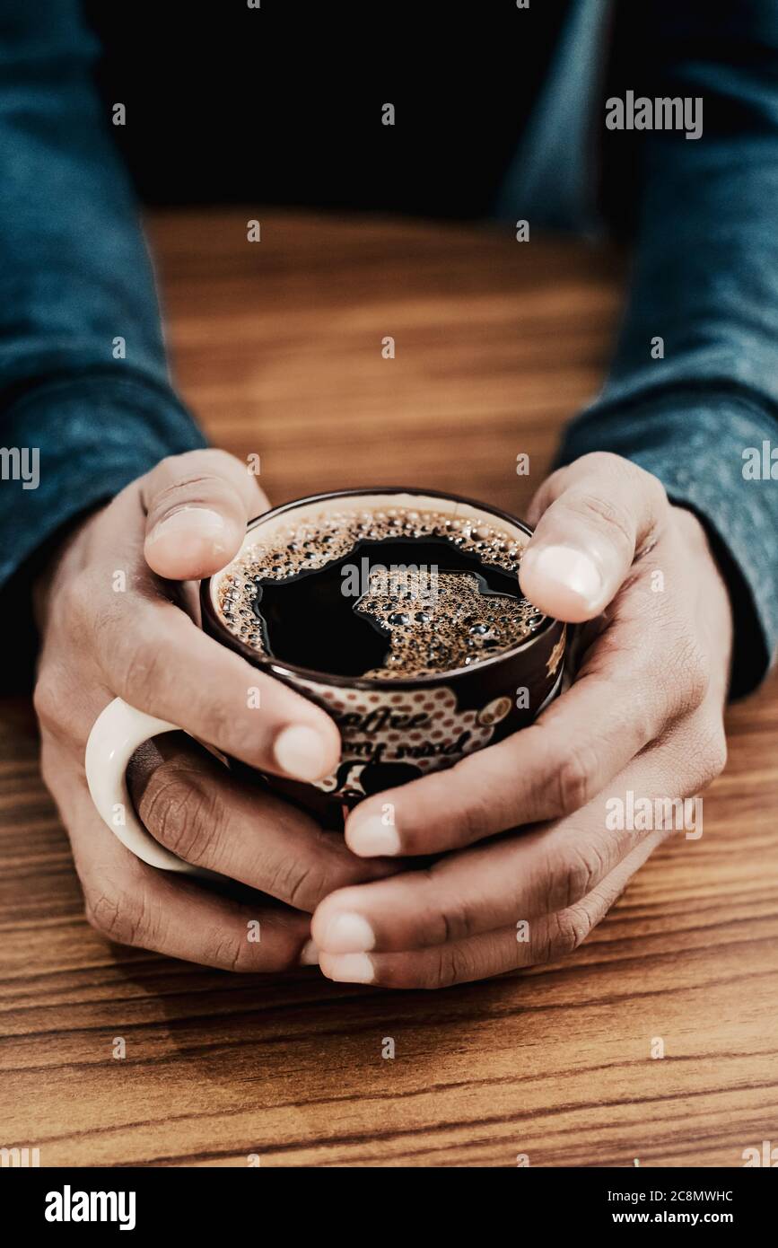 Hand holding coffee on a table Stock Photo - Alamy