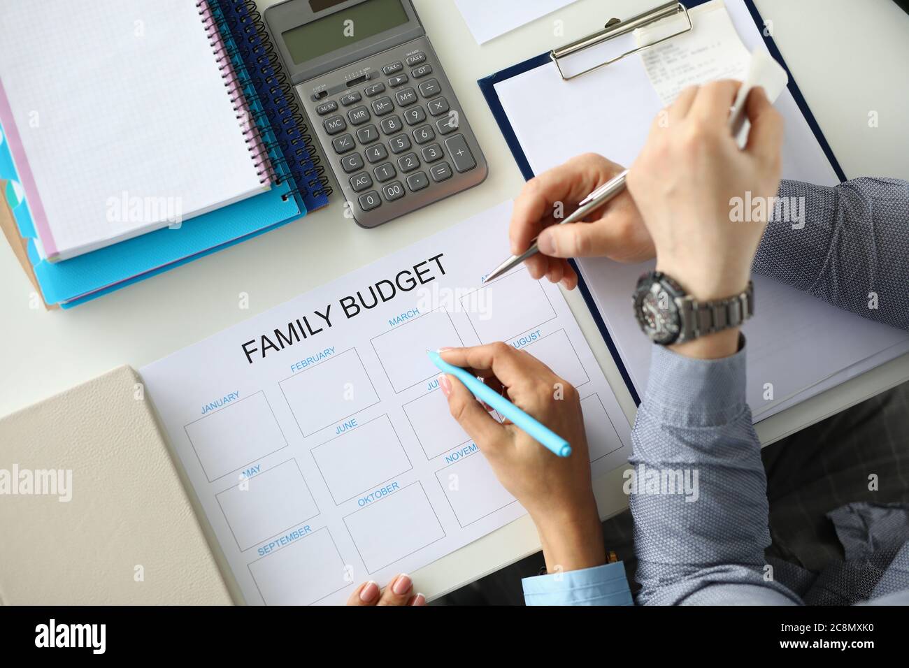 Male and female hands fill out family budget table at home on white ...