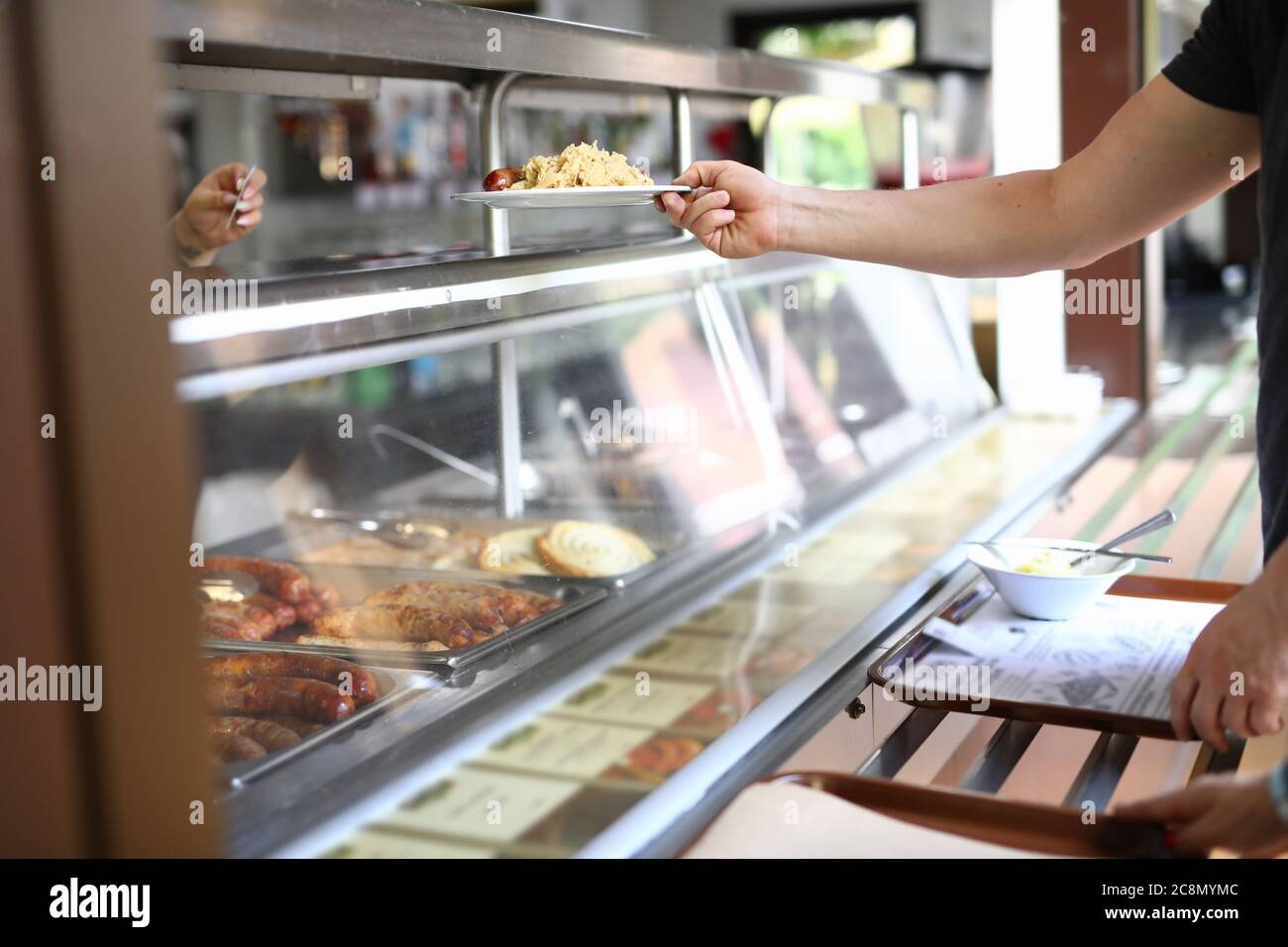 Man stand behind counter of ready-made food in dining room and hold ...