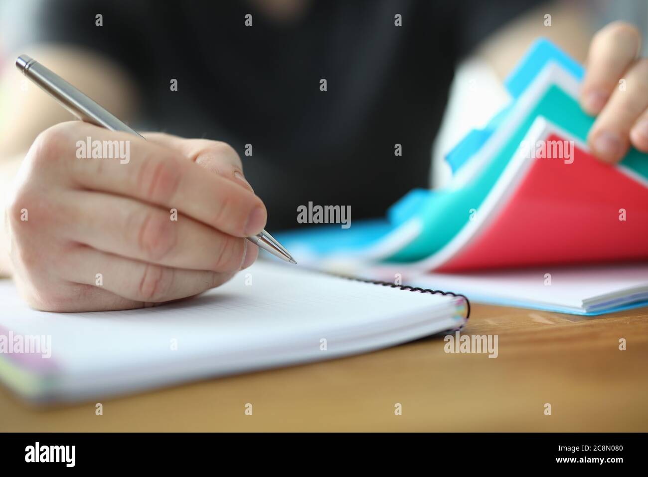 Man write with pen in blank pad and leafs through folder with documents ...