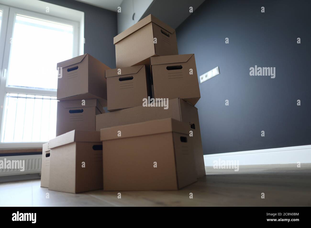 Many cardboard boxes stand one over one in empty room. Cargo ...