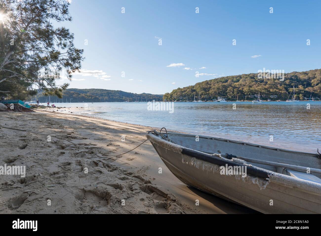 A small alloy boat (dinghy) or tinnie sits on the sand beside the quiet ...