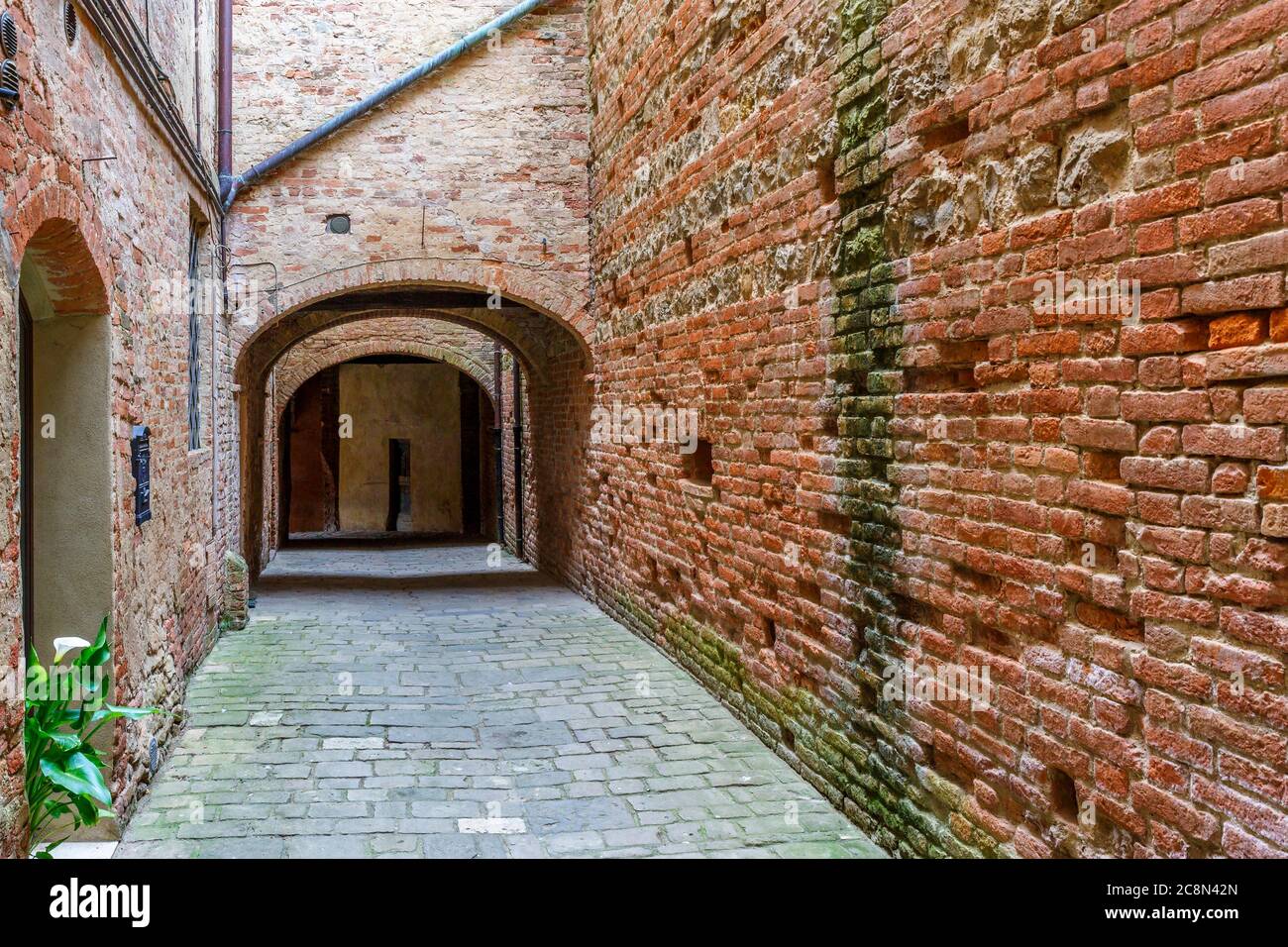 Alley with brick walls in an old village Stock Photo - Alamy