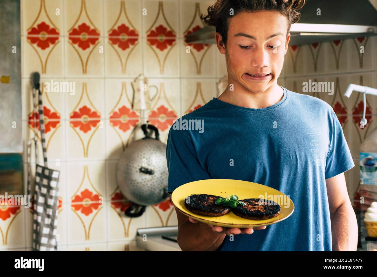 Young teenager with burned too cooked hamgurger with funny expression ...