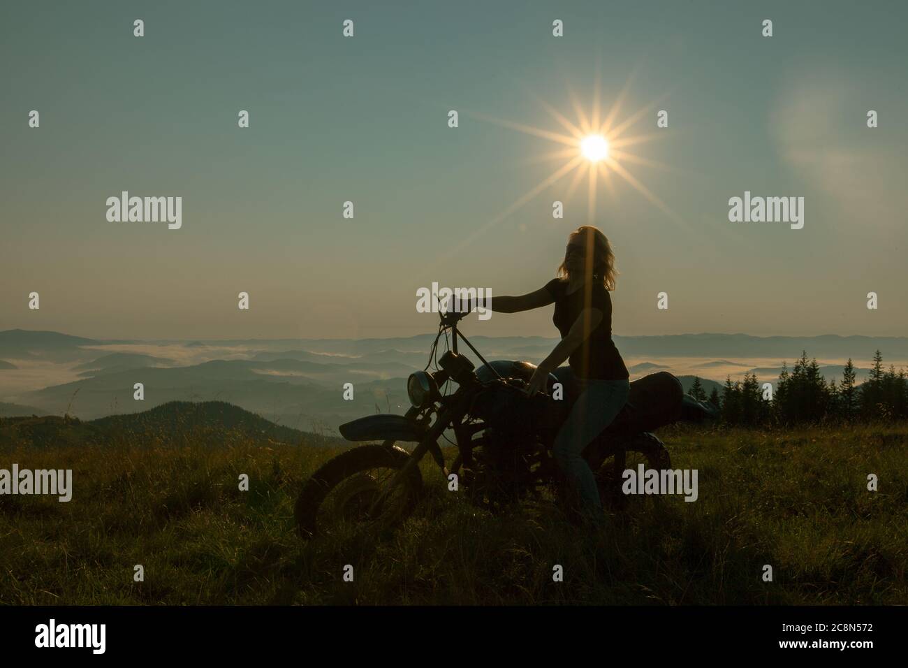 girl on a motorcycle high in the mountains stopped to rest at dawn ...
