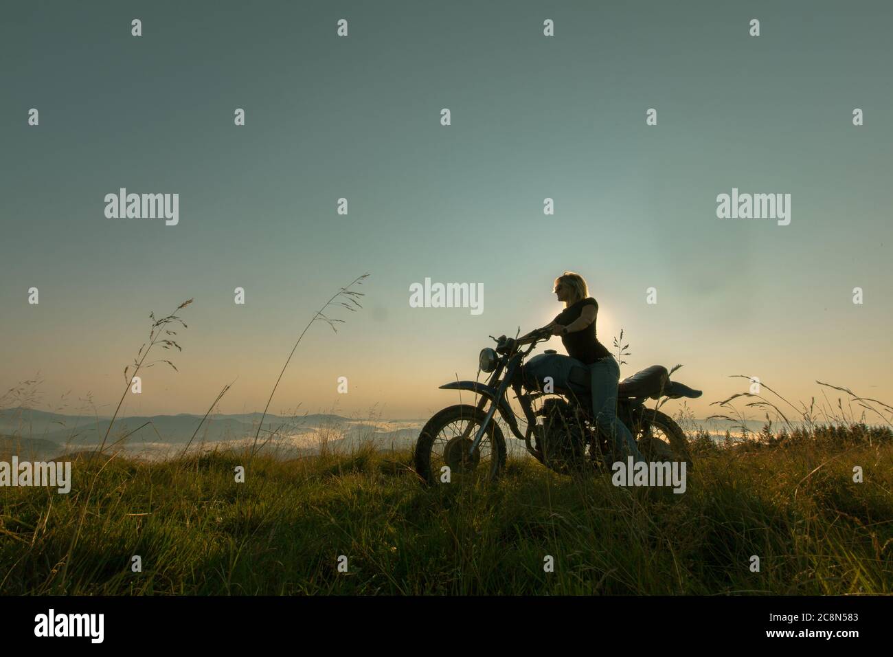 girl on a motorcycle high in the mountains stopped to rest at dawn ...