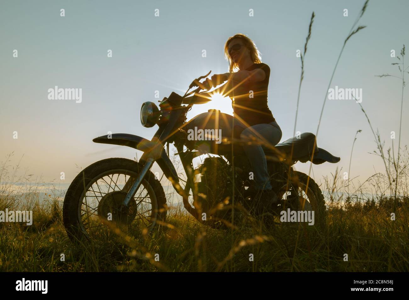 girl on a motorcycle high in the mountains stopped to rest at dawn ...