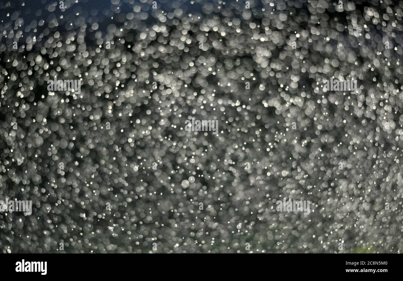 flying waterdrops against the sunrays on a dark background image Stock ...