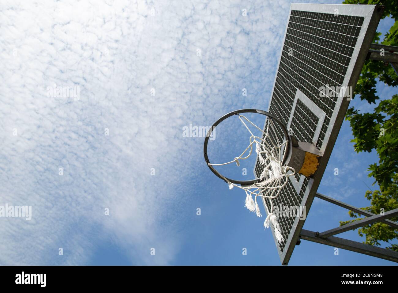 A broken basketball net dangles from a hoop attached to a metal ...
