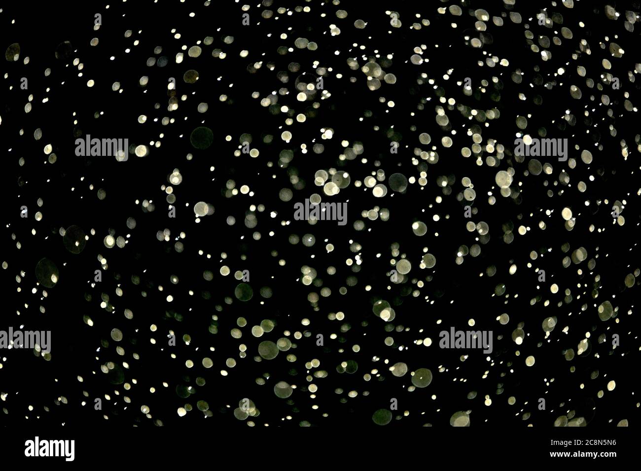 flying waterdrops against the sunrays on a dark background image Stock ...