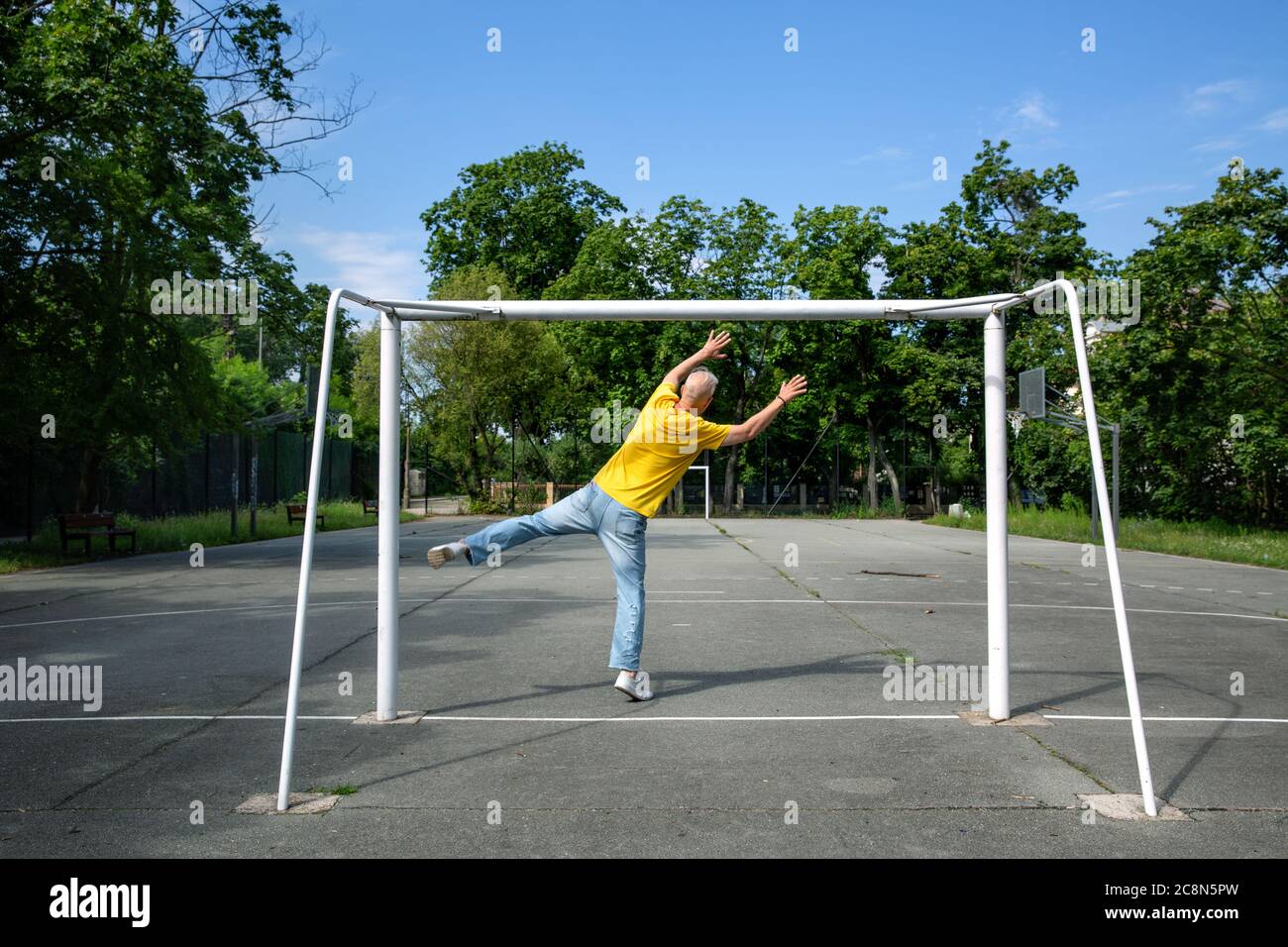 a gray-haired man catches an imaginary ball in a soccer goal Stock ...