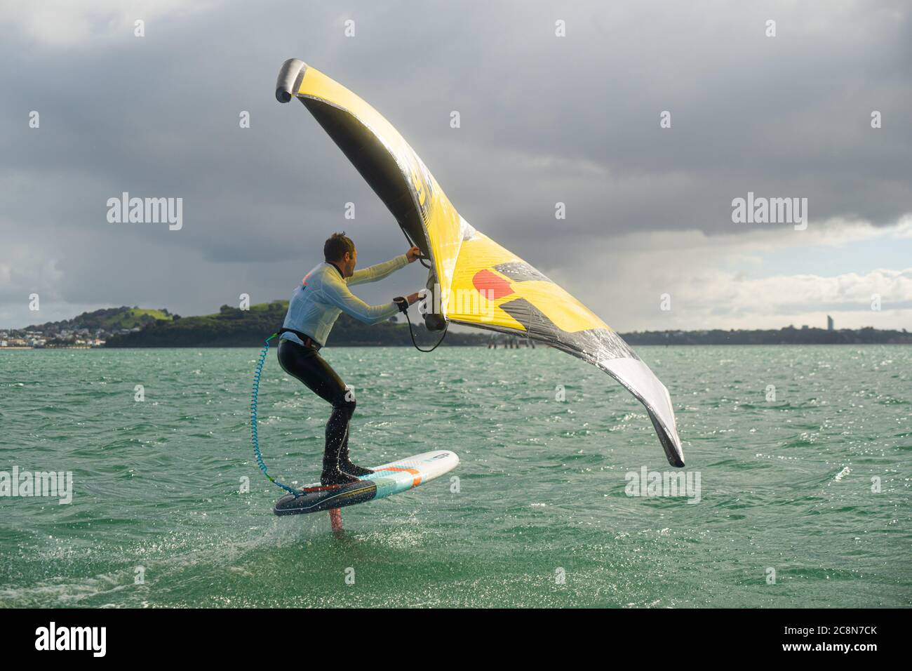 A young man wingfoils in Auckland harbour, using a hand held inflatable ...