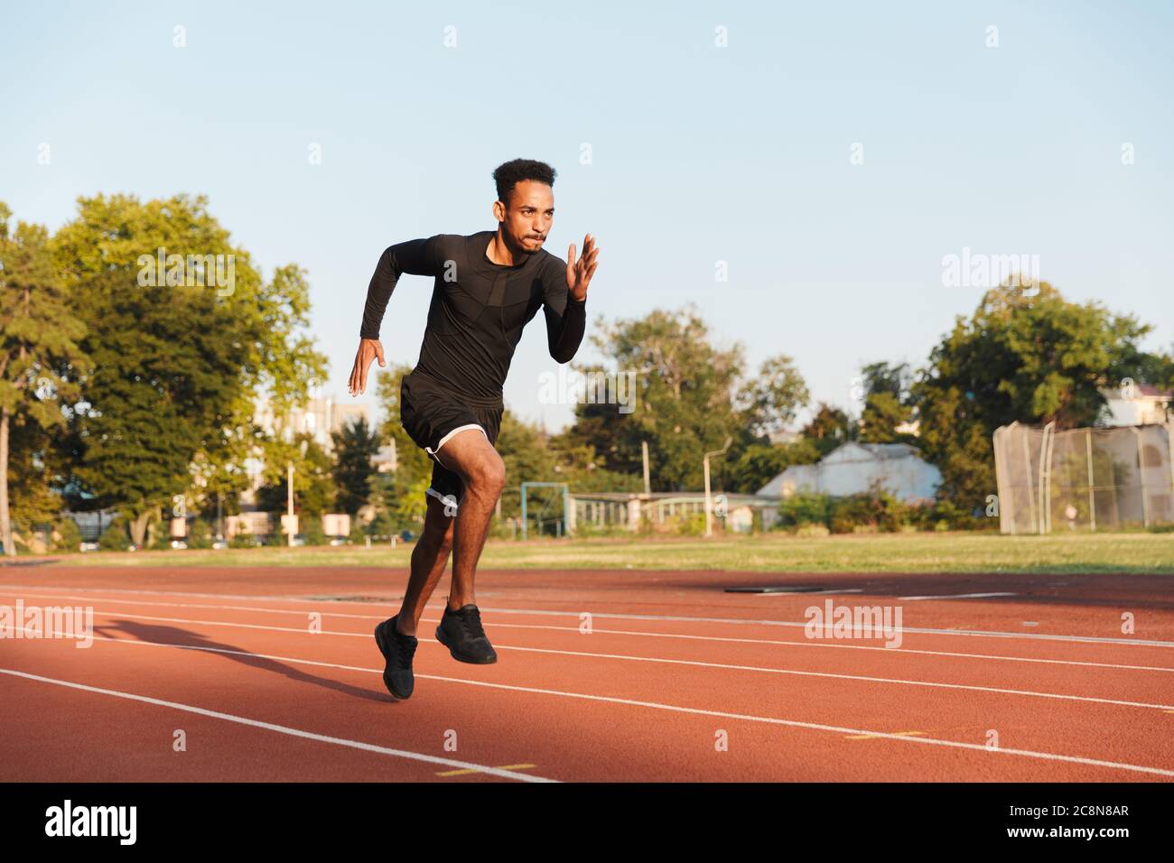 Image of athletic african american man running on sports stadium ...