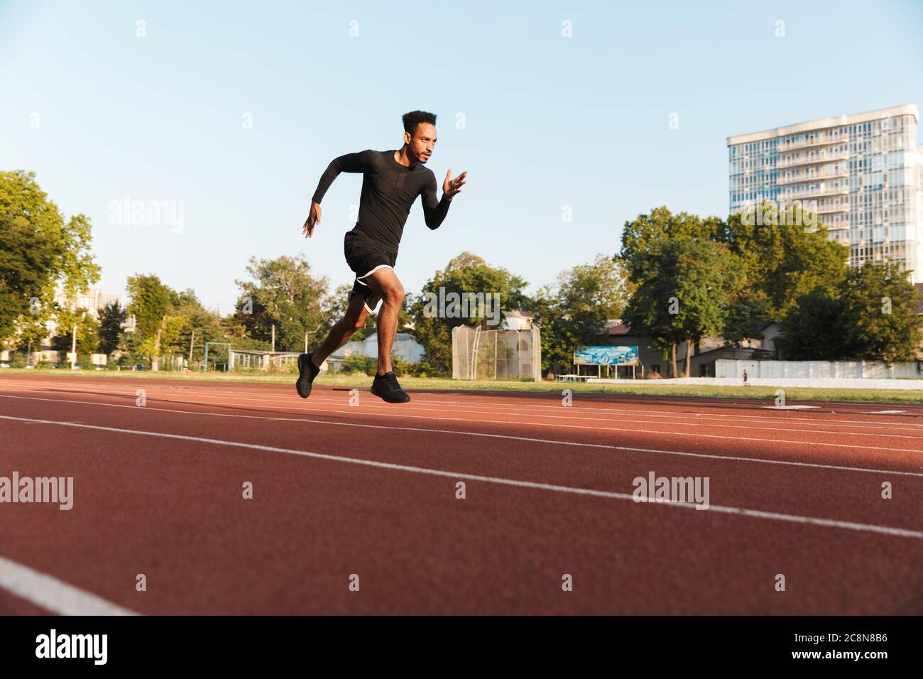 Image of strong african american man running on sports stadium outdoors ...