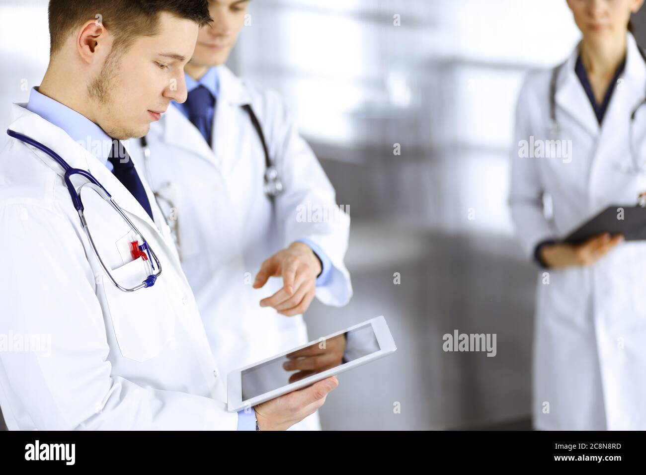 Group of doctors are checking medical names on a computer tablet, with ...