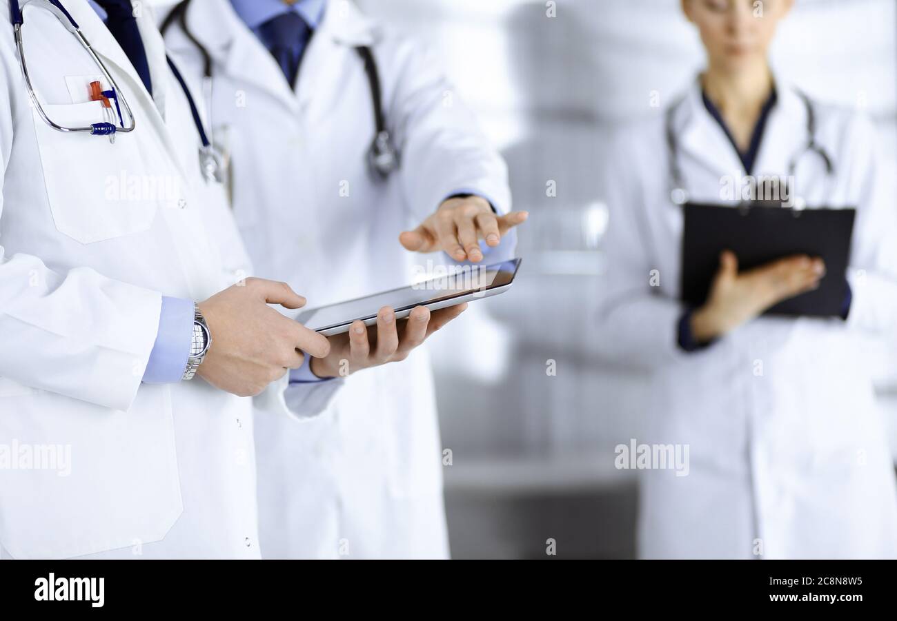 Group of unknown doctors use a computer tablet to check up some medical ...