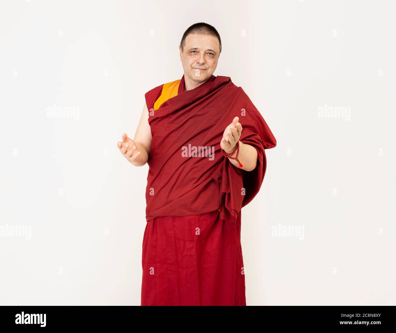 portrait of a monk in a red and yellow lamas robe with ritual ...