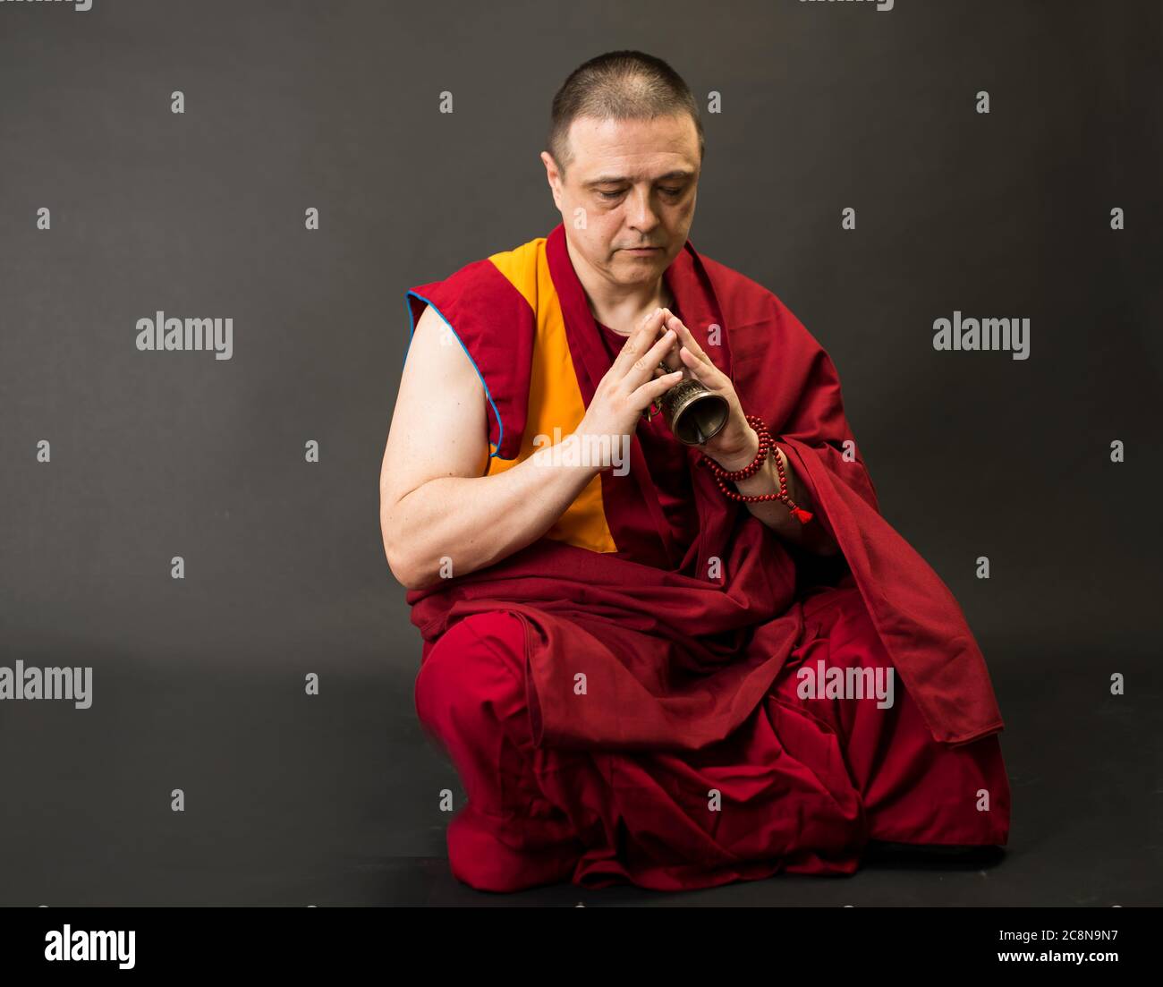 The monk holds a prayer drum in his hand. portrait of a Buddhist monk ...