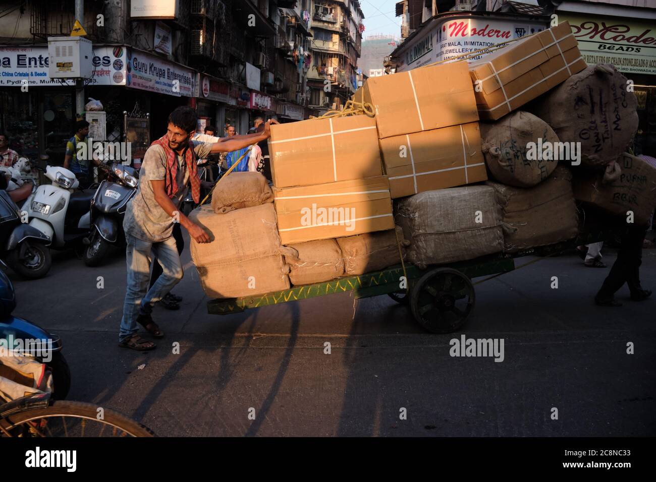 Two men steer a heavy handcart through Kalbadevi Rd. in Bhuleshwar ...