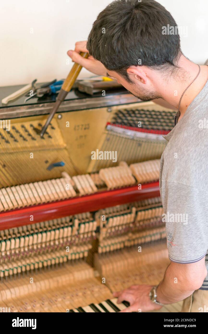 Piano tuning process. closeup of hand and tools of tuner working on ...