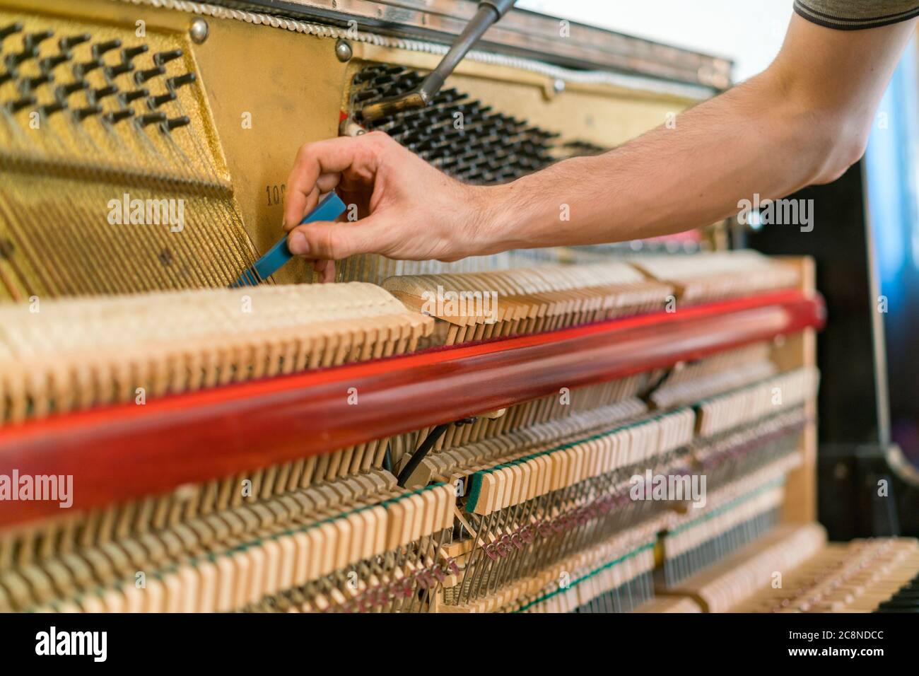 Piano tuning process. closeup of hand and tools of tuner working on ...