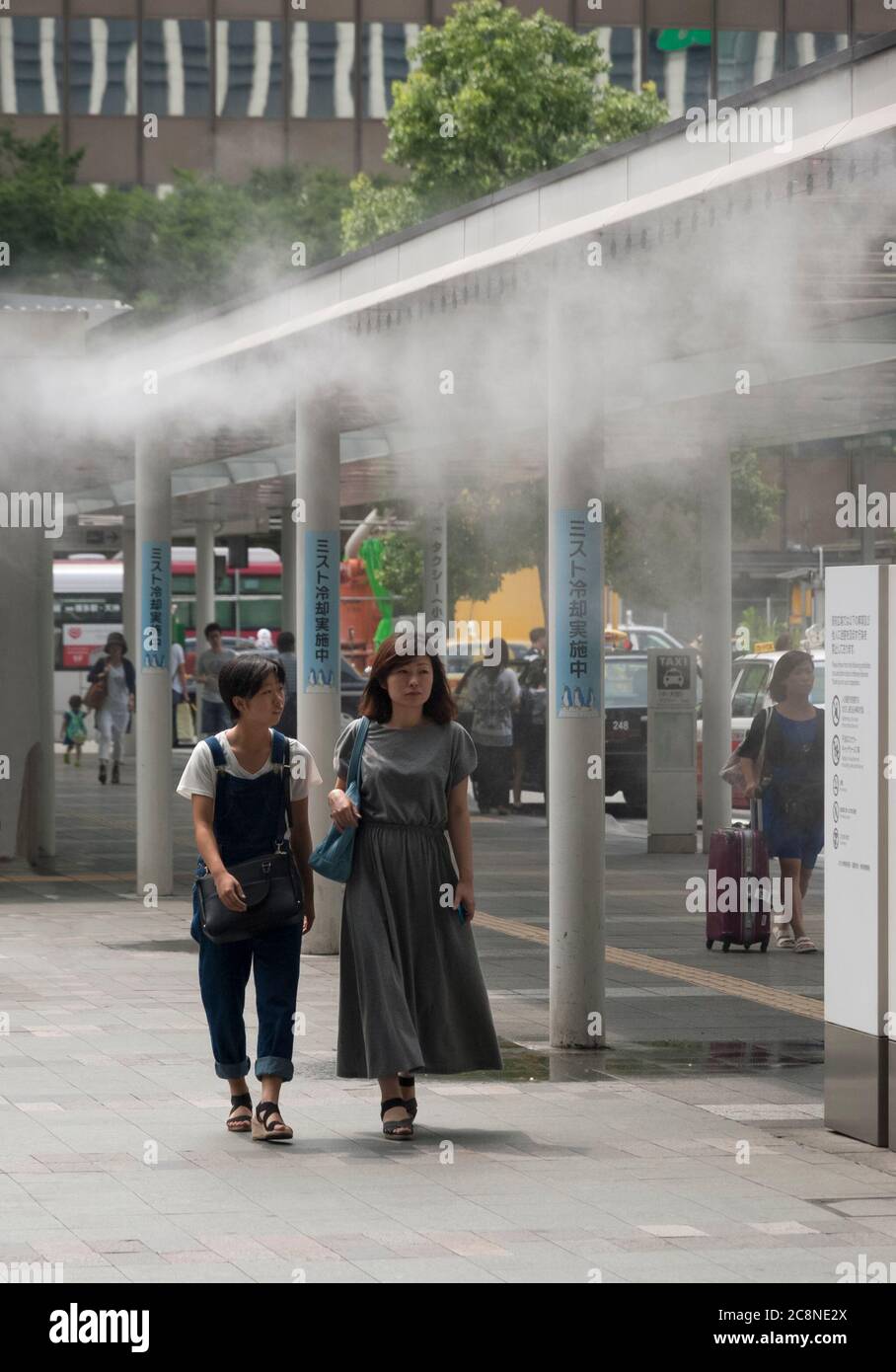 Water mist systems keeping people cool outside the Hakata railway ...