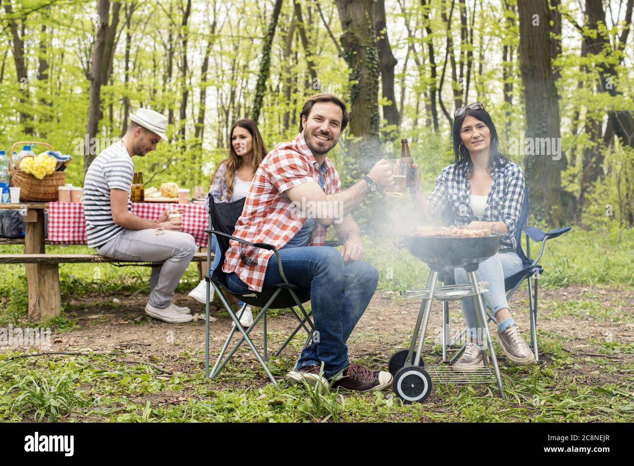 Group of Caucasian friends making barbecue in the forest at summer ...