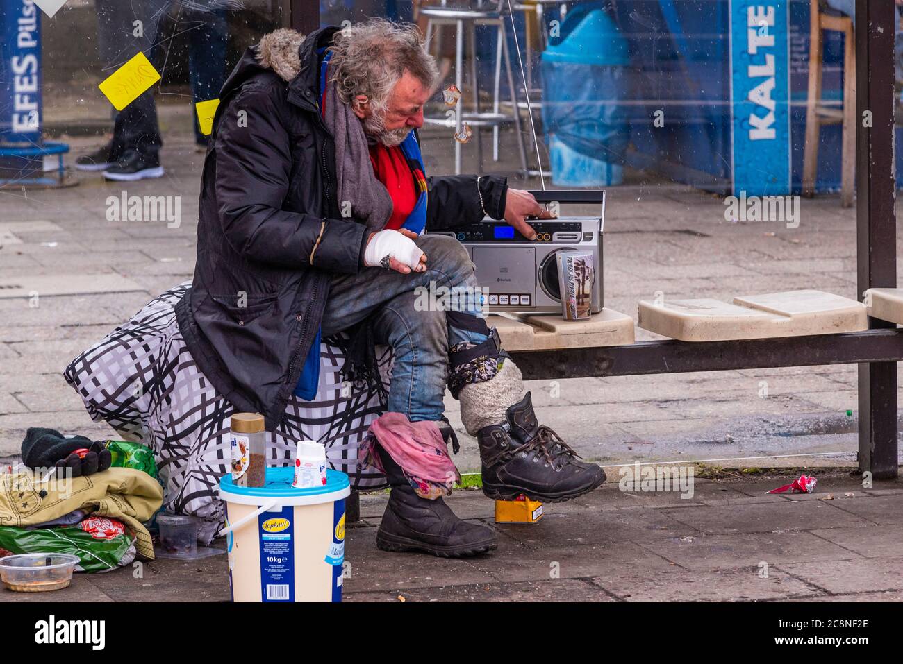 A homeless man with a radio, a homeless man seated in a tram station ...