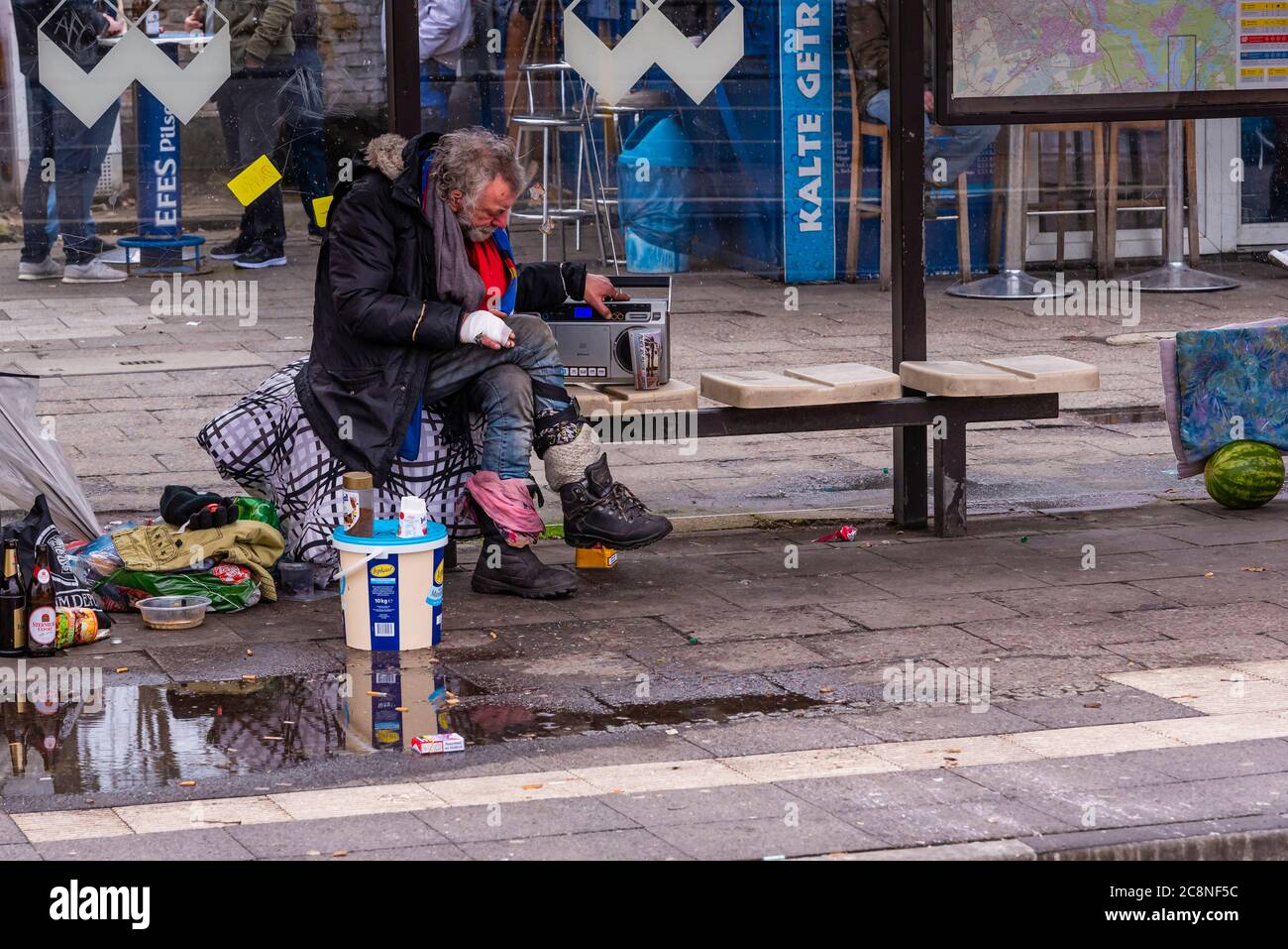 A homeless man with a radio, a homeless man seated in a tram station ...