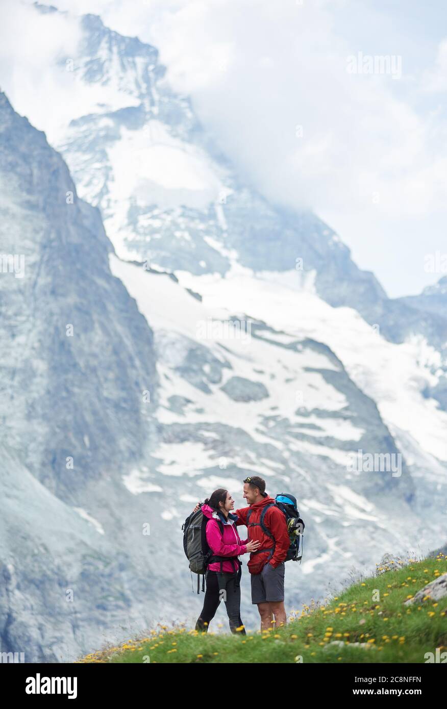 Loving couple with backpacks hugging, beautiful mountains scenery on ...