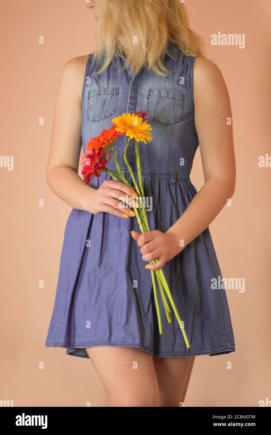 Cheerful young lady and flowers chamomile in hands. Beautiful attractive lady standing with ...