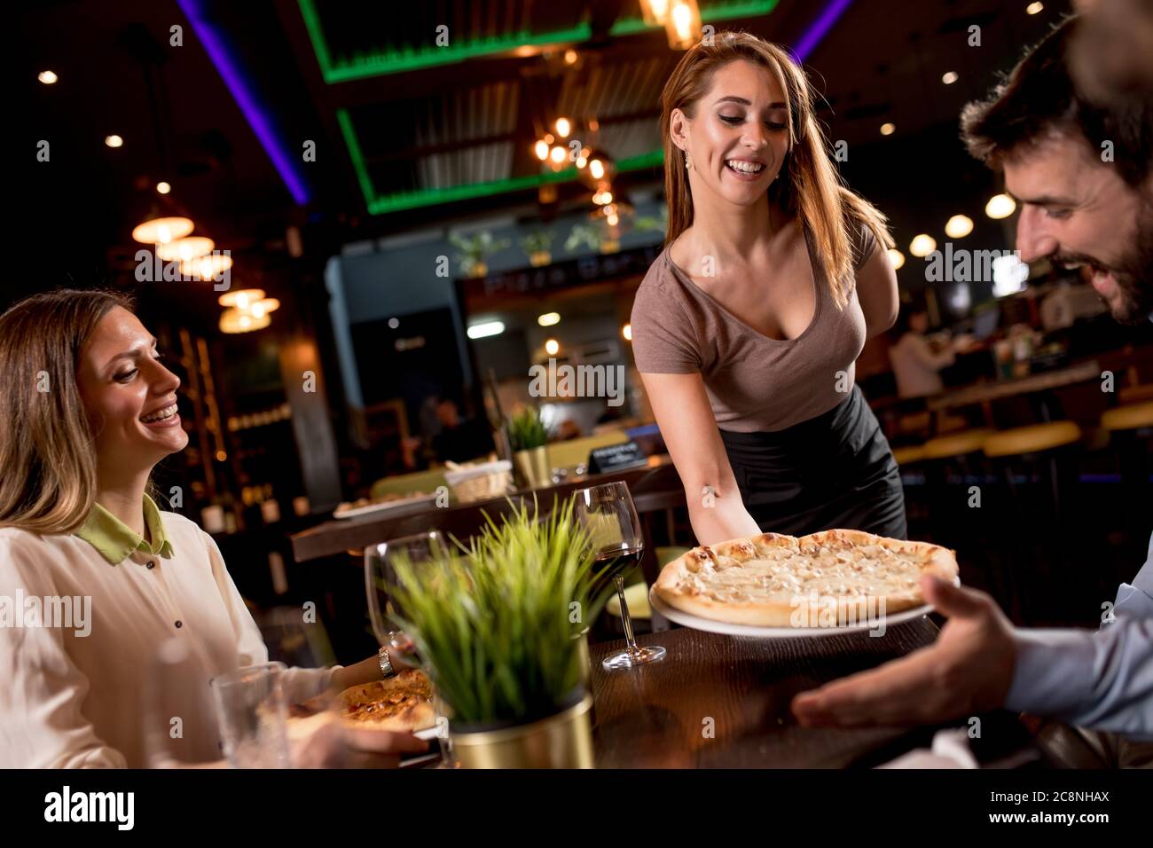Pretty waiter woman serving group of friends with food in the ...