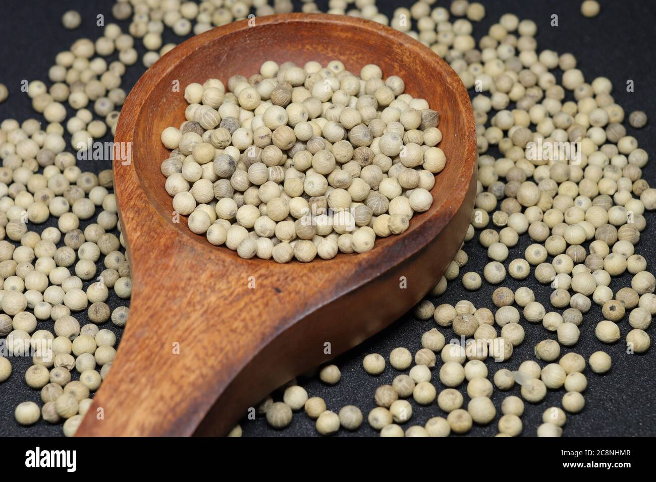 White pepper grains isolated on black background Stock Photo - Alamy