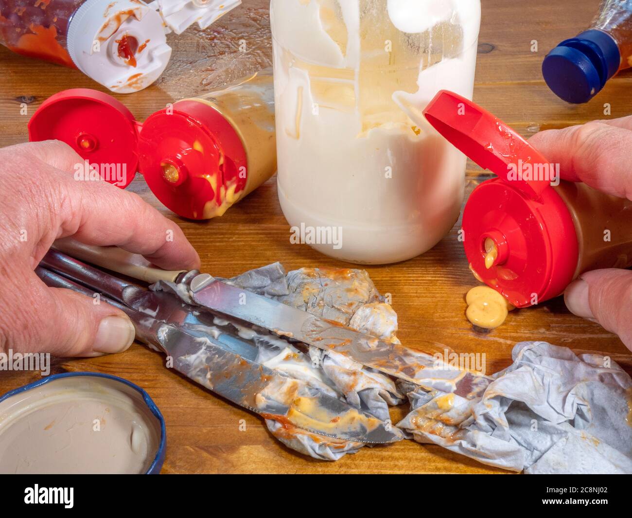 Closeup of a man’s hands clearing up the mess on a table created by ...