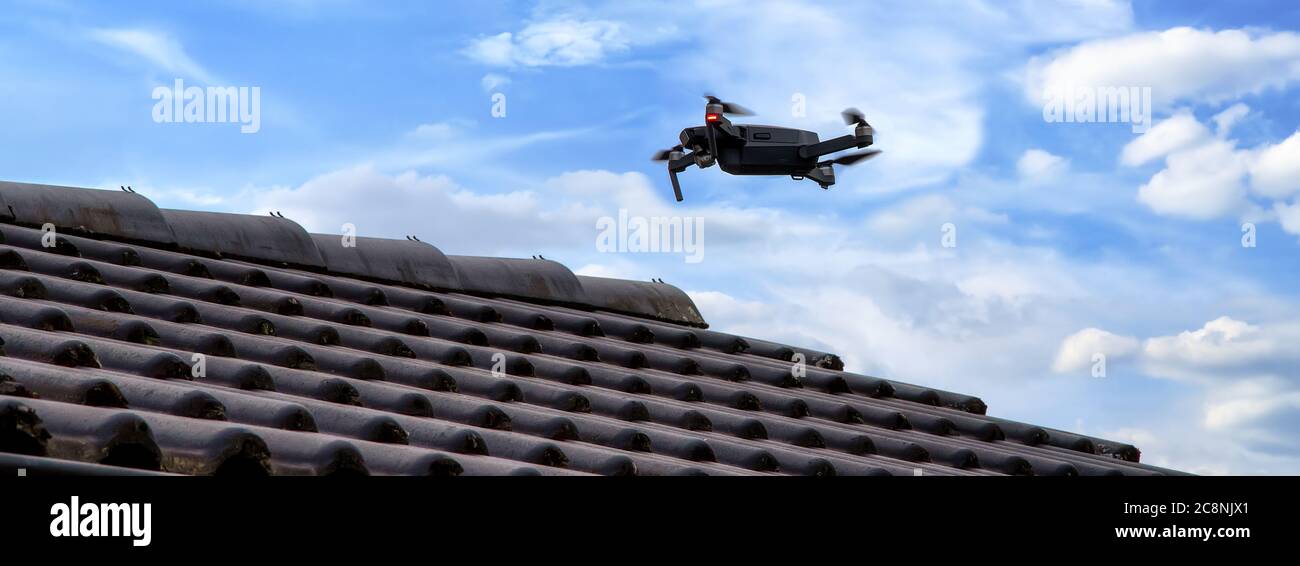 Drone in the air inspecting the roof over the house. Close-up of drone ...