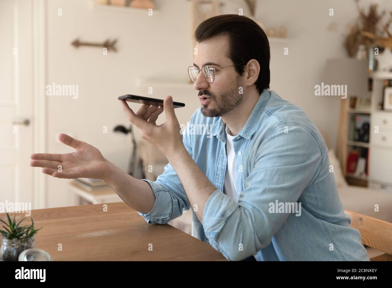 Young man talk on cellphone using voice assistant Stock Photo - Alamy