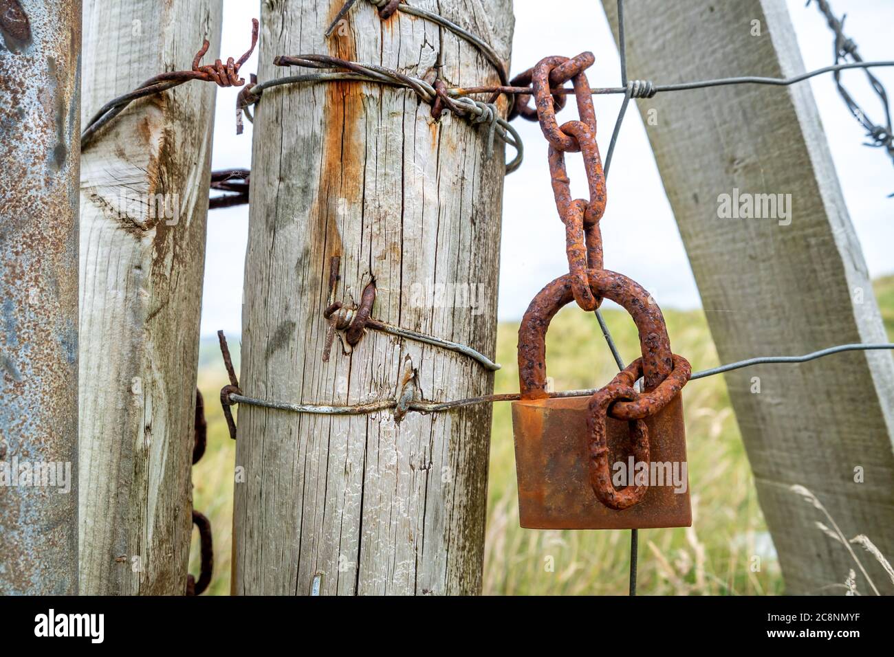 Rusty lock and chain hanging at fence next to gate Stock Photo - Alamy