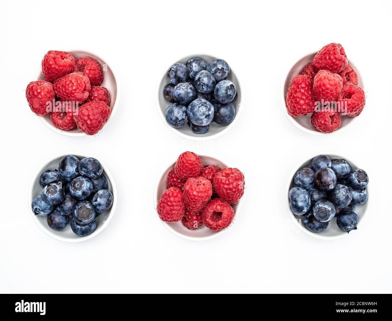 Blueberries and raspberries in white bowls isolated on white background ...