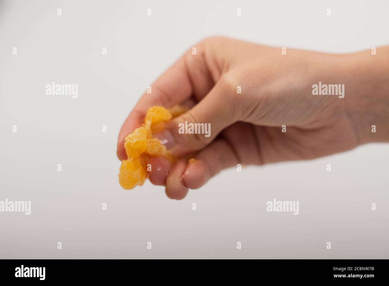 Hand squashing orange Stock Photo - Alamy