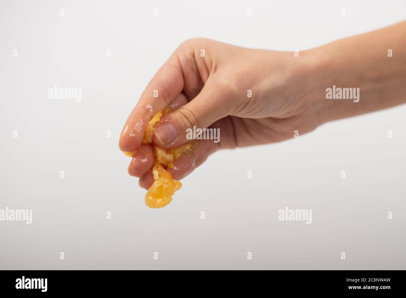 Hand squashing orange Stock Photo - Alamy