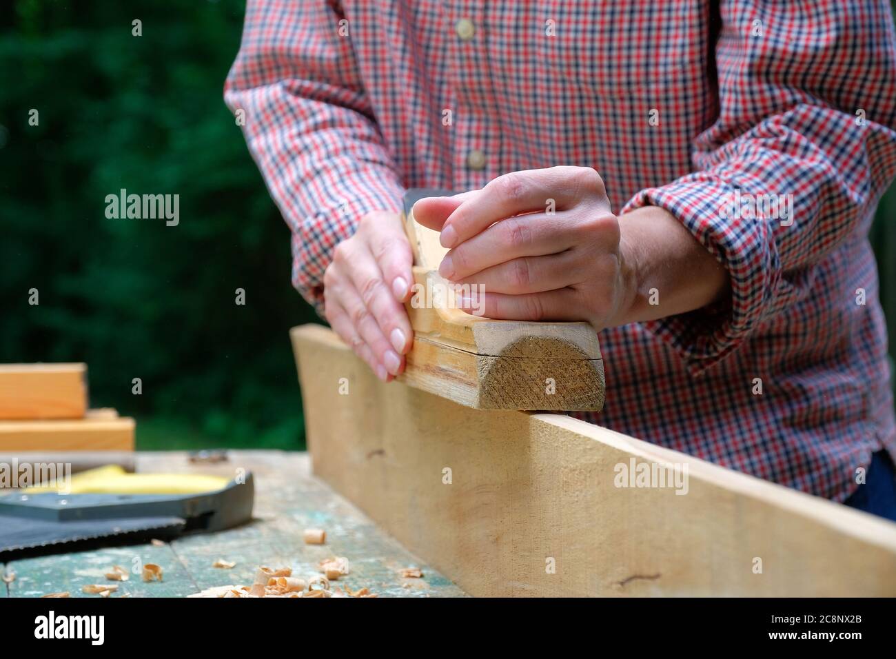 Caucasian craftswoman working in her workshop using carpentry plane ...
