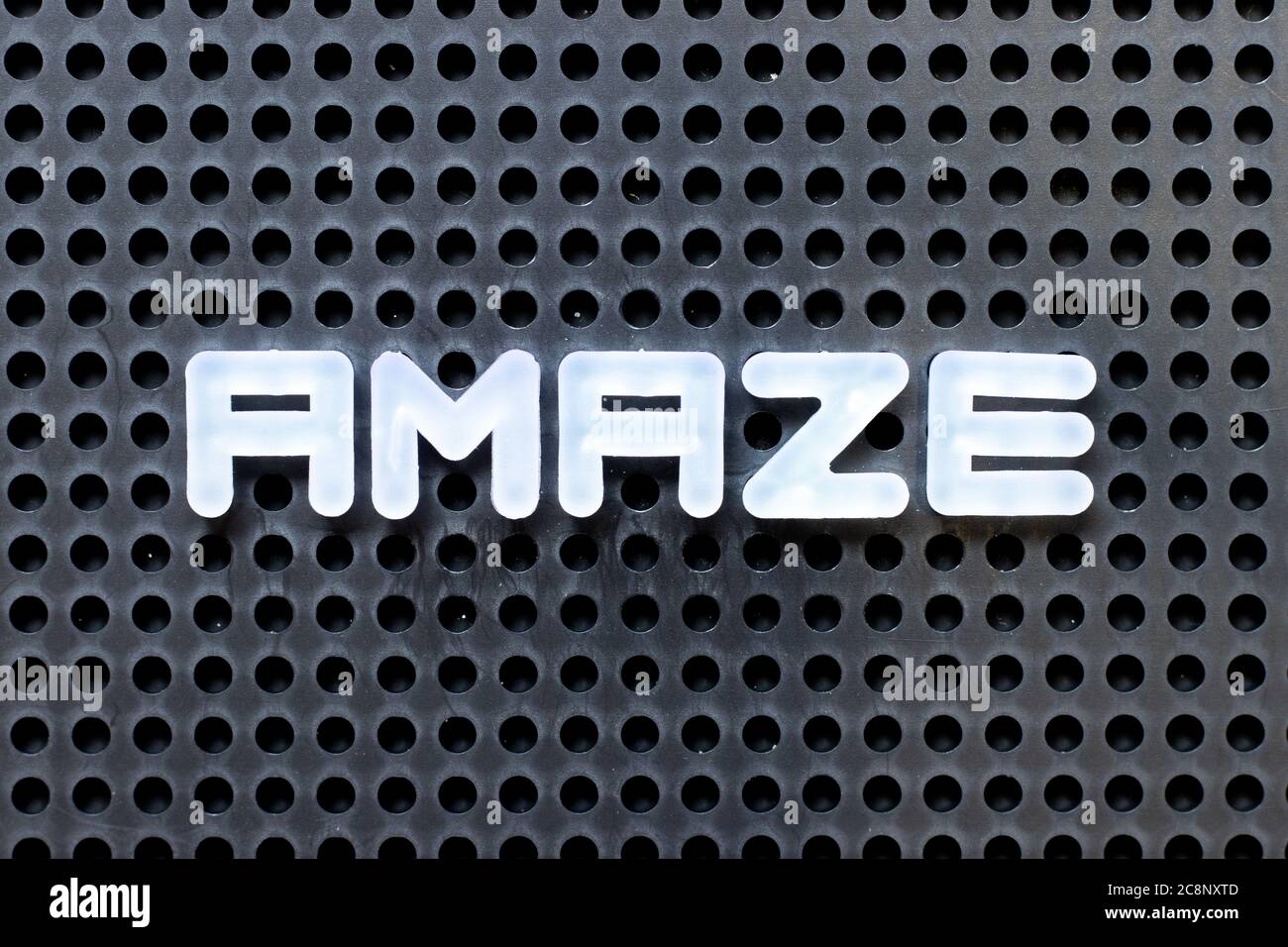 White color alphabet with word amaze on black pegboard background Stock ...