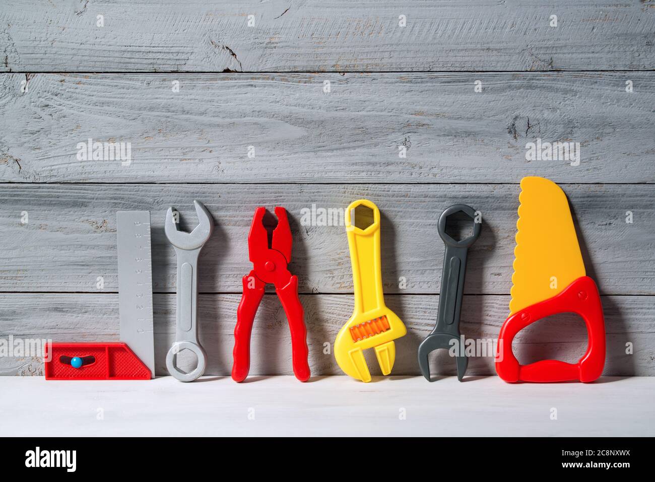 Set of plastic toy tools for children in a line on a wooden background ...