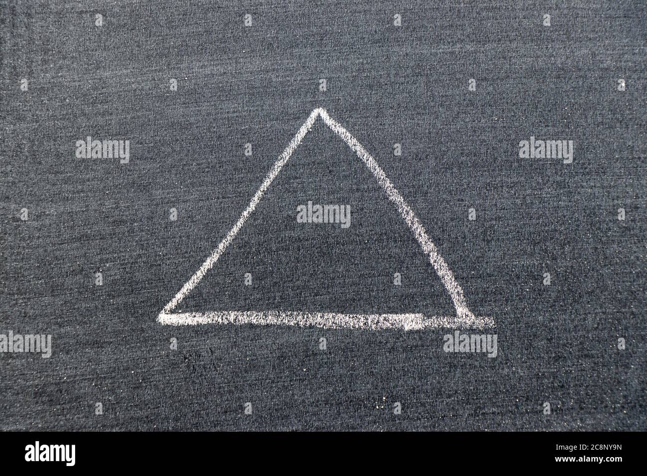 White color chalk hand drawing in triangle shape on black board ...