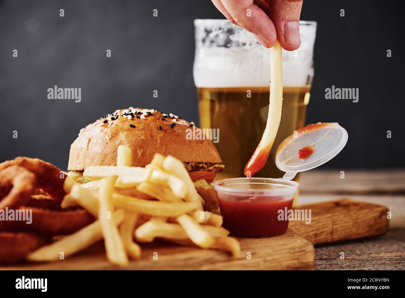 Different types of fastfood and snacks and glass of beer on table ...