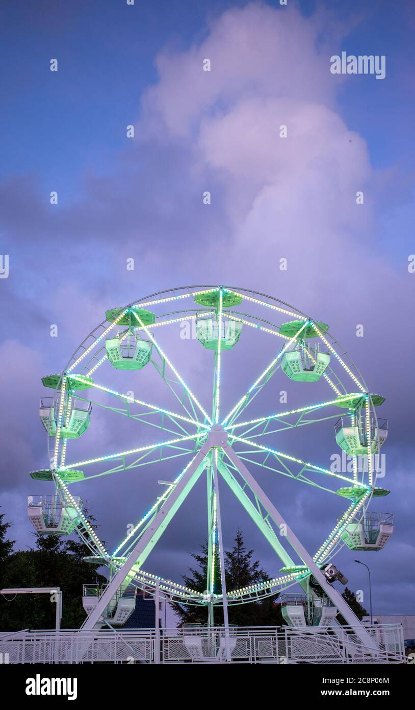 colourfully illuminated Ferris wheel stands in front of a dark sky ...