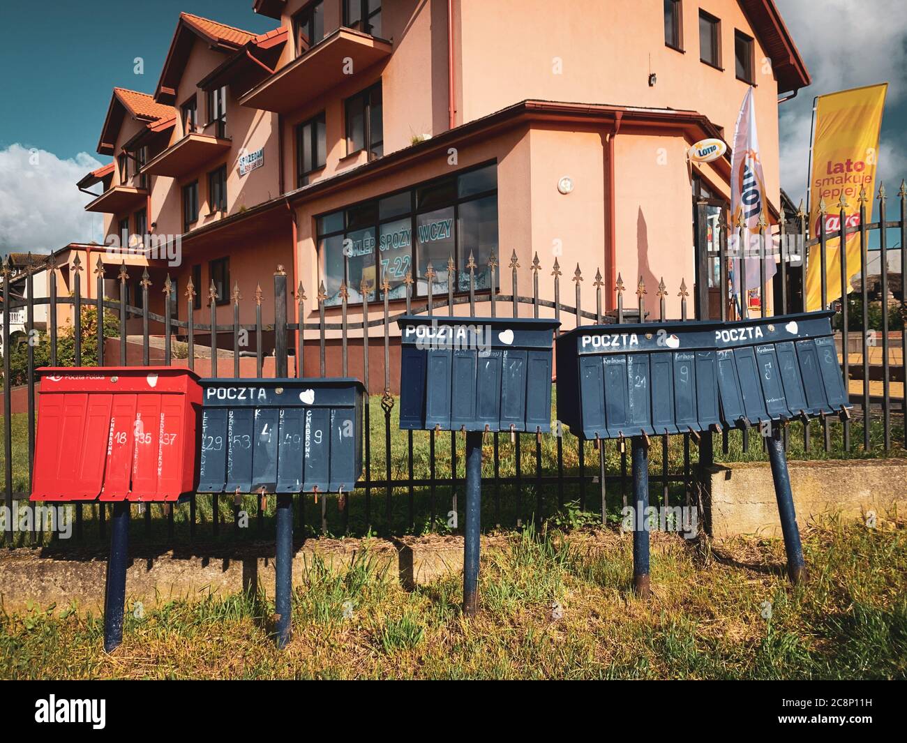 red and blue mailboxes standing on a street in a village in Poland ...