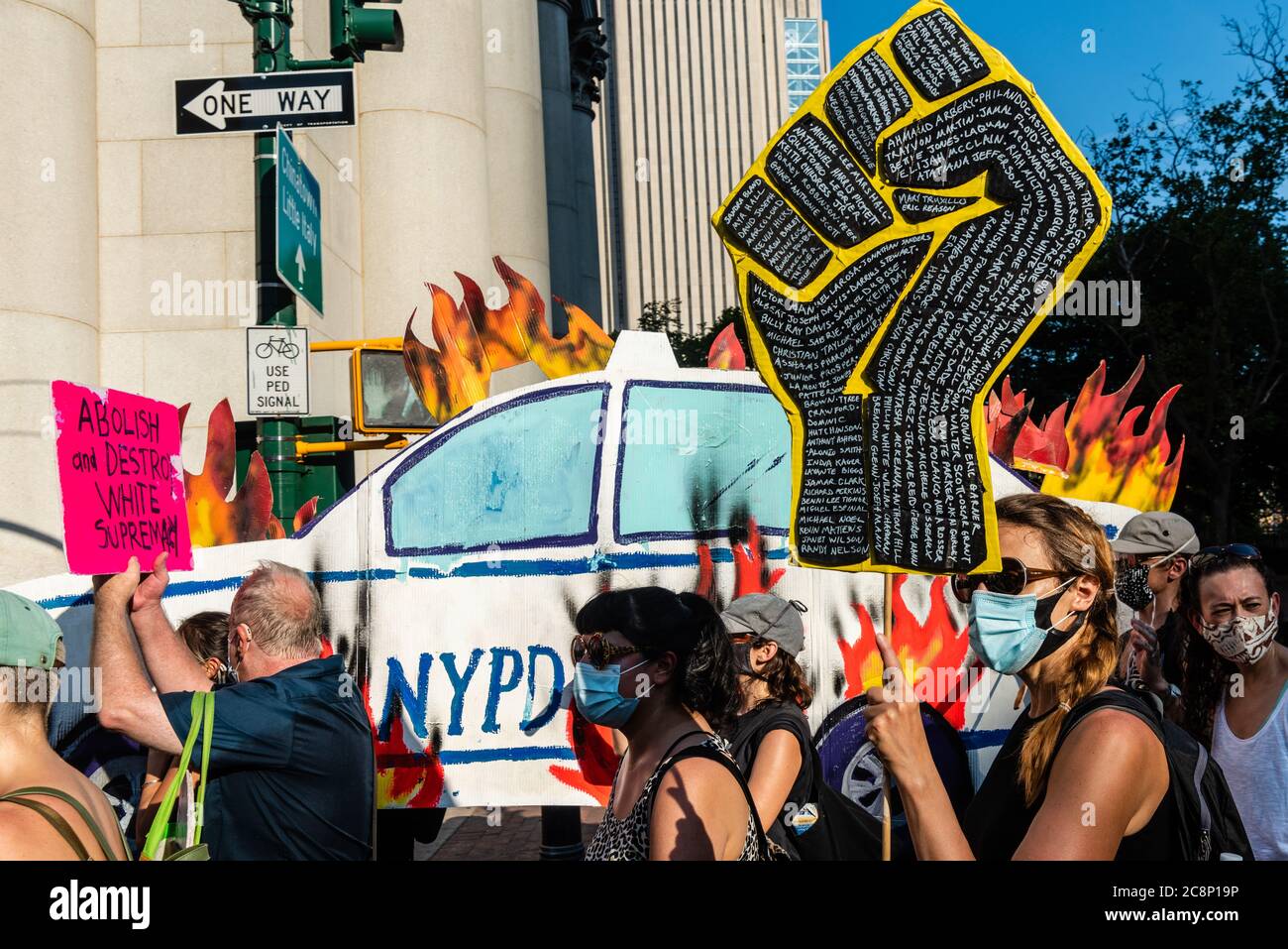 Protesters carry a cardboard cut-out of an NYPD police car depicting it ...