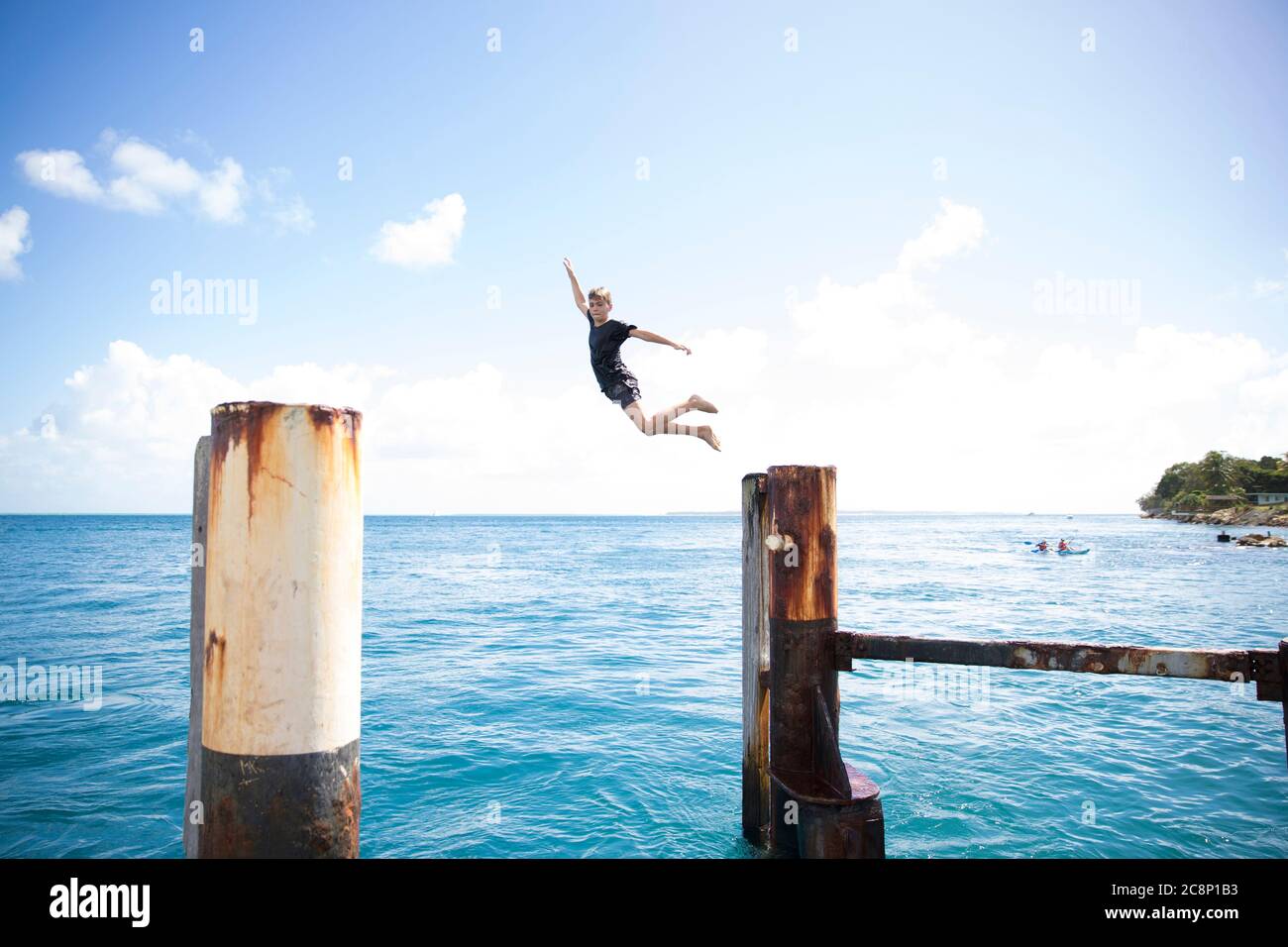 Boy jumping off a wooden jetty, North Stradbroke Island, Moreton Bay ...