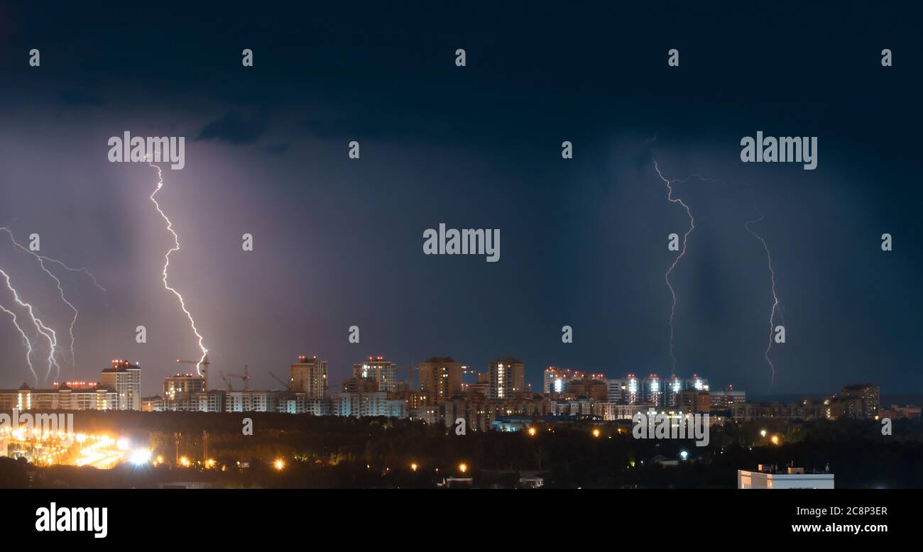 Several bright lightning bolts strike the ground in the night city ...